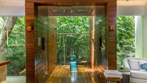 Um spa moderno com painéis de madeira, um espaço envidraçado e vista para vegetação exuberante.