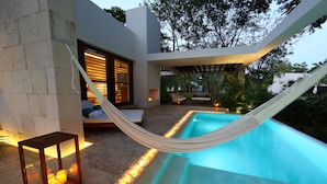 Uma área de piscina moderna ao ar livre, com rede, assentos e iluminação ambiente.