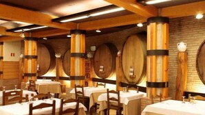 Um restaurante com paredes de barris de madeira, mesas com toalhas brancas e cadeiras de madeira.