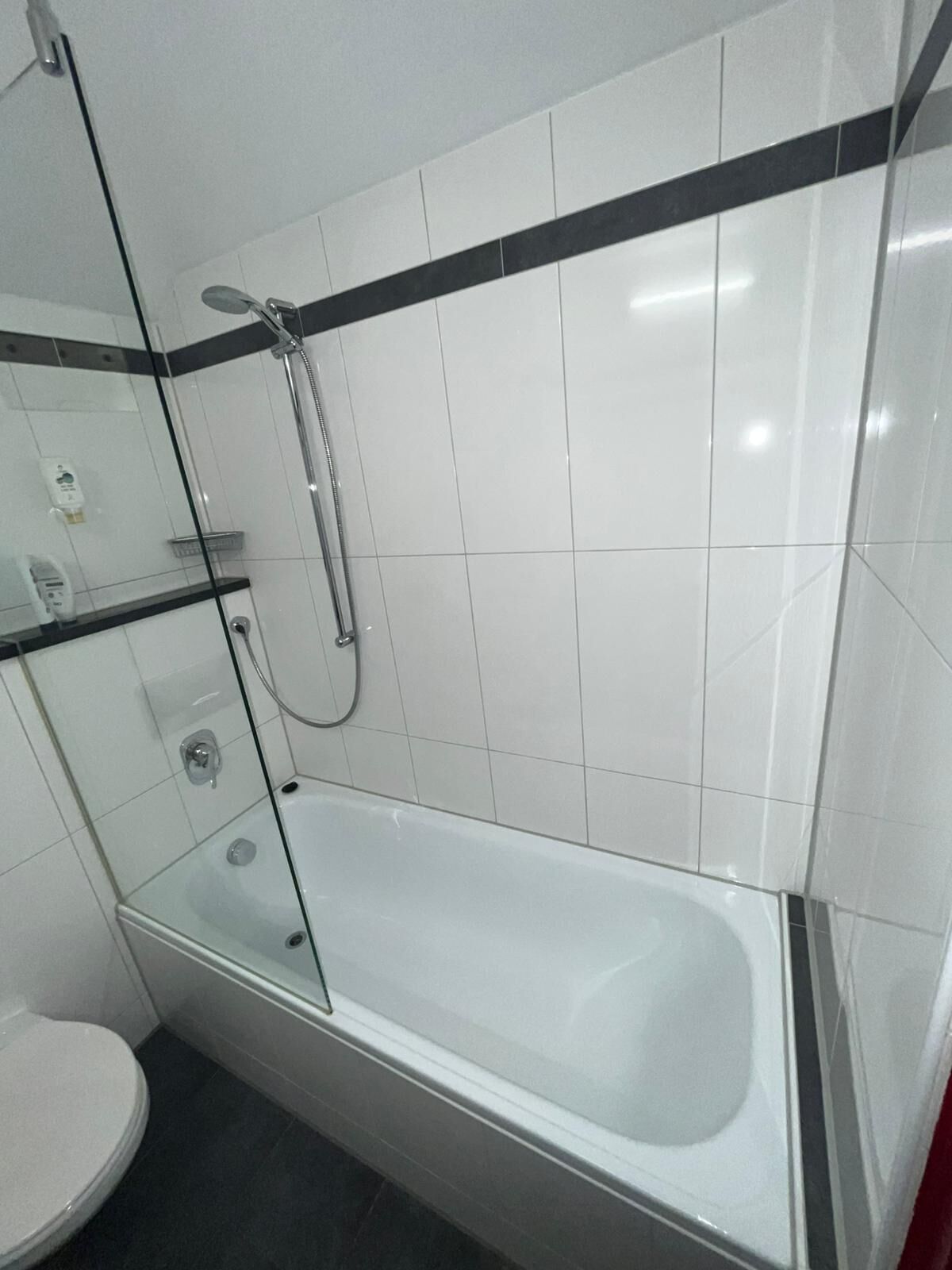 Casa de banho moderna com chuveiro envolto em vidro, banheira branca e sanita.