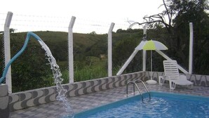 Piscina com um elemento aquático, cercada por uma grade e um muro decorado.