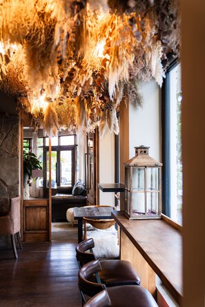 Um interior acolhedor com teto de madeira, um candeeiro e um espaço de estar junto a uma janela.