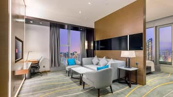 Quarto de hotel moderno com vista para a cidade, um sofá, uma escrivaninha e uma cama.