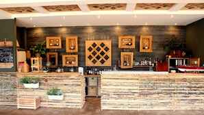 Uma área de bar com prateleiras de madeira, espaço para vinhos e cardápio em lousa.