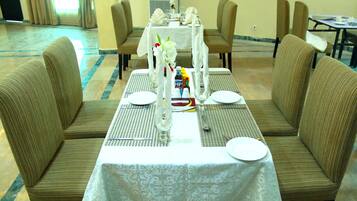 Uma área de jantar com uma mesa posta para quatro pessoas, cercada por cadeiras estofadas.
