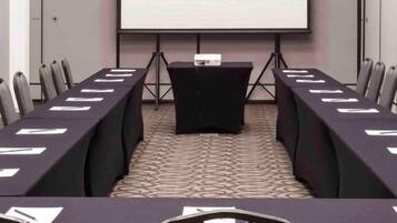 Uma sala de conferência com uma mesa comprida, cadeiras e uma tela de projeção exibindo o logotipo da Royal Palm Tower.