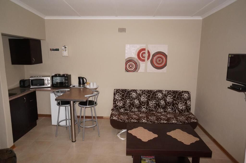 Um espaço compacto para viver, com cozinha compacta, sofá, mesa de jantar com cadeiras e TV de tela plana.