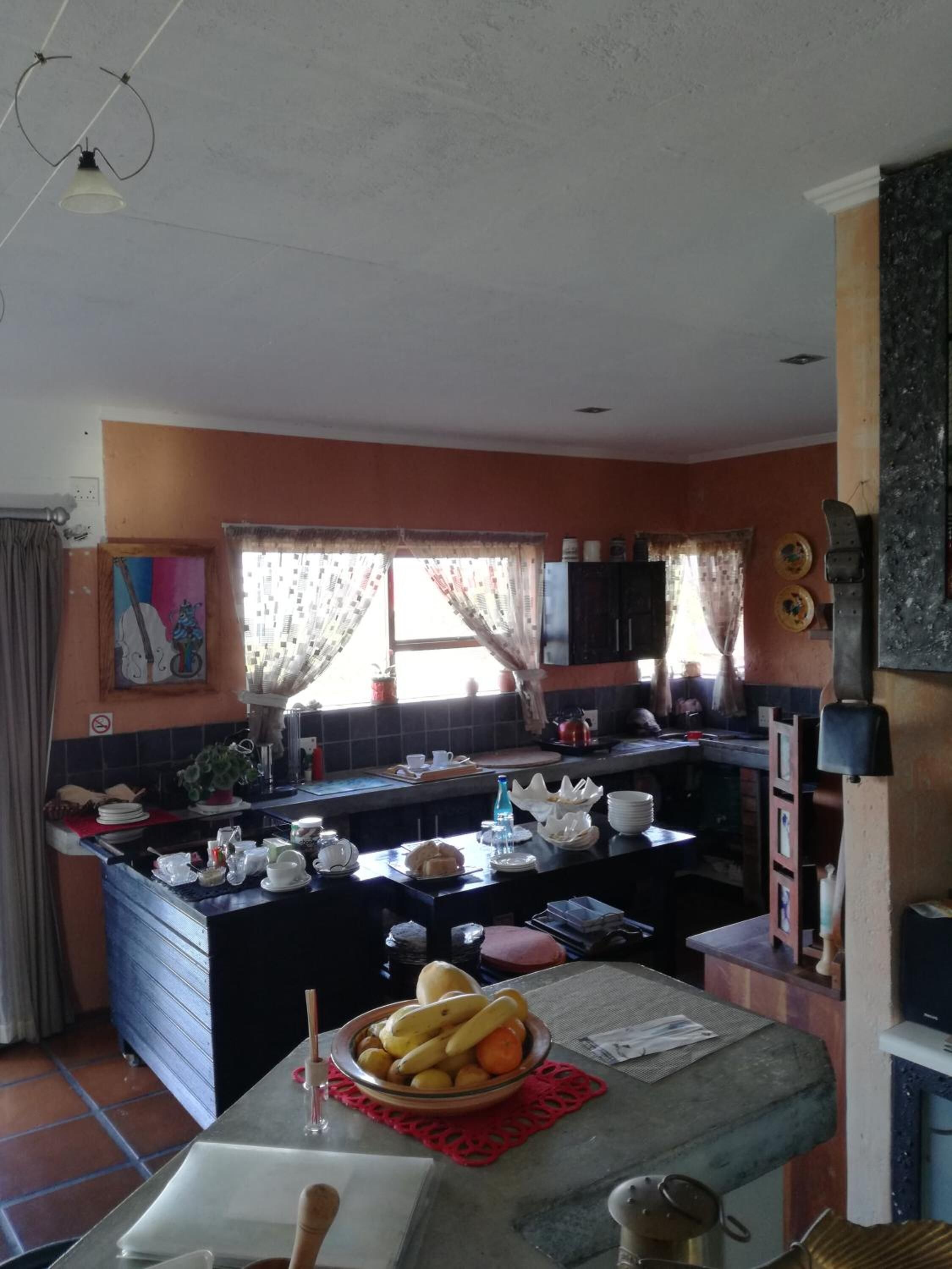 Cozinha compacta com ilha central, mesa de jantar e janela com cortinas.