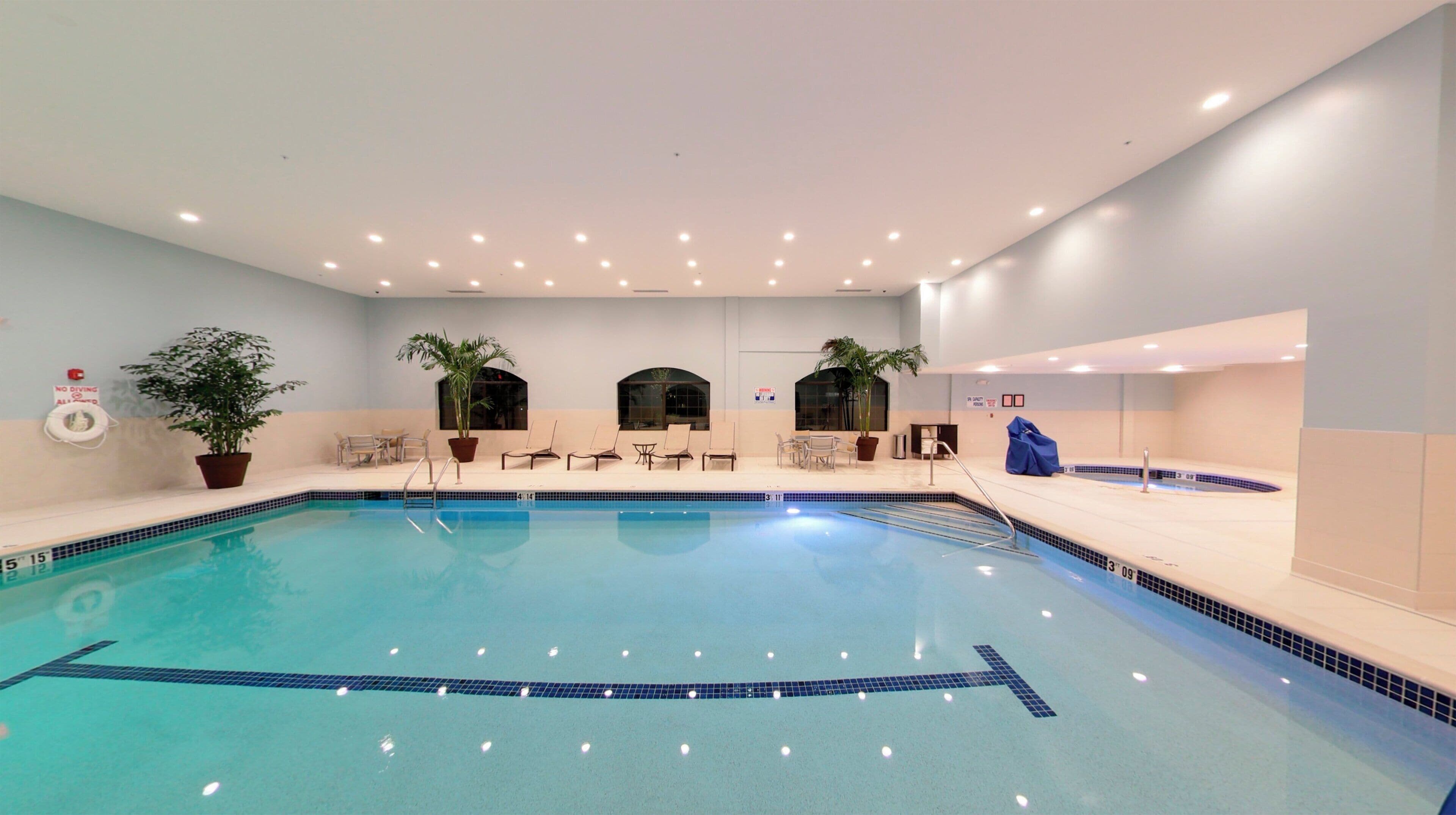 Piscina interior com água cristalina, várias pistas de natação e espreguiçadeiras nas laterais.