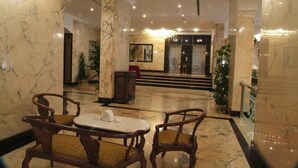 Um hall de entrada com piso de mármore, um balcão de recepção e uma escadaria para um andar superior.