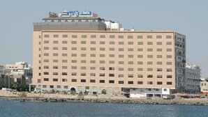 Um hotel grande, com vários andares e fachada uniforme, situado perto de um corpo d'água.