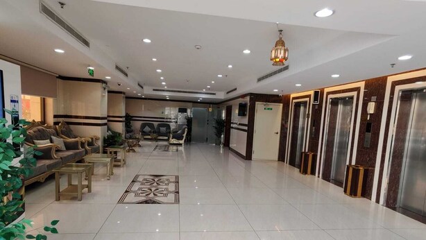 Um hall amplo com área de recepção, assentos e elevadores.