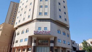 Um edifício alto de hotel com vários andares e uma entrada central.