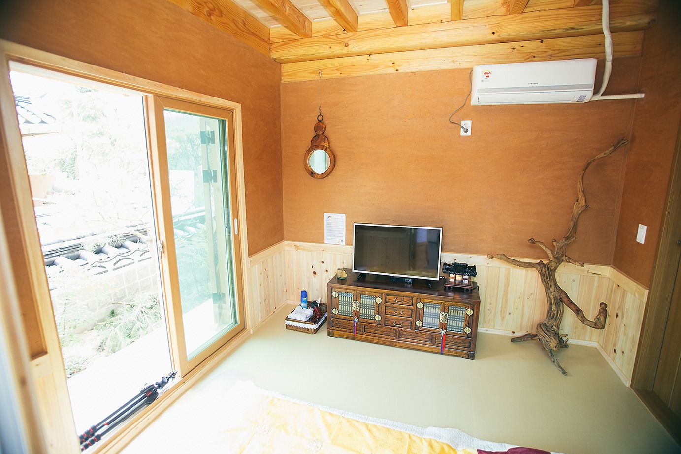 Quarto com uma grande porta de vidro deslizante, uma televisão em um armário de madeira e um ar-condicionado fixado na parede.