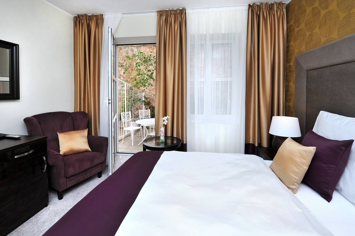 Quarto de hotel com cama, escrivaninha, cadeira, mesa e vista para o exterior.
