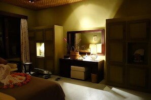 Quarto de hotel com cama, escrivaninha, espelho e janela.