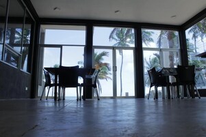 Quarto espaçoso com grandes janelas, uma mesa de jantar e cadeiras.