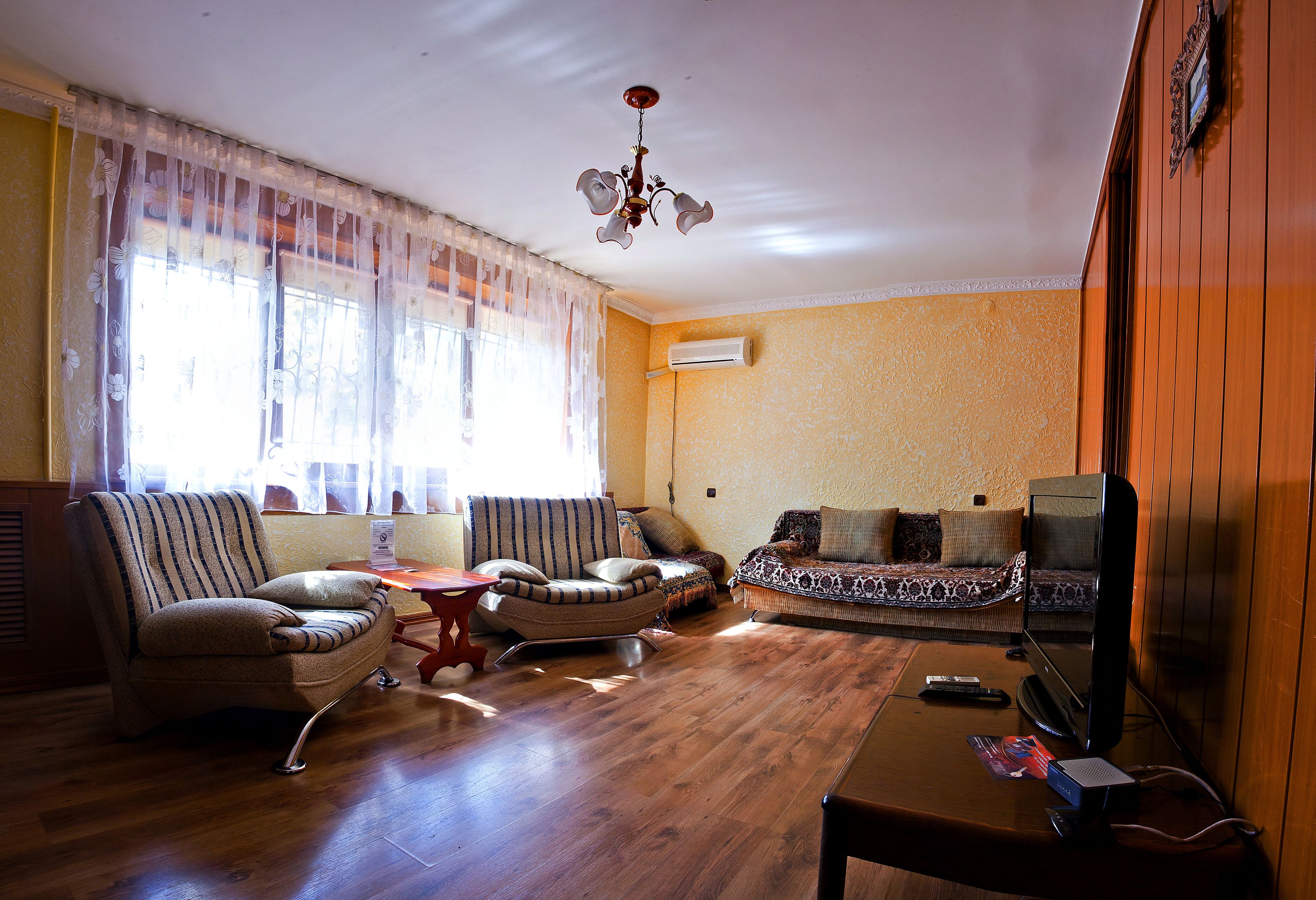 Uma sala de estar com sofá, poltronas, mesa de centro, televisão e ventilador de teto.
