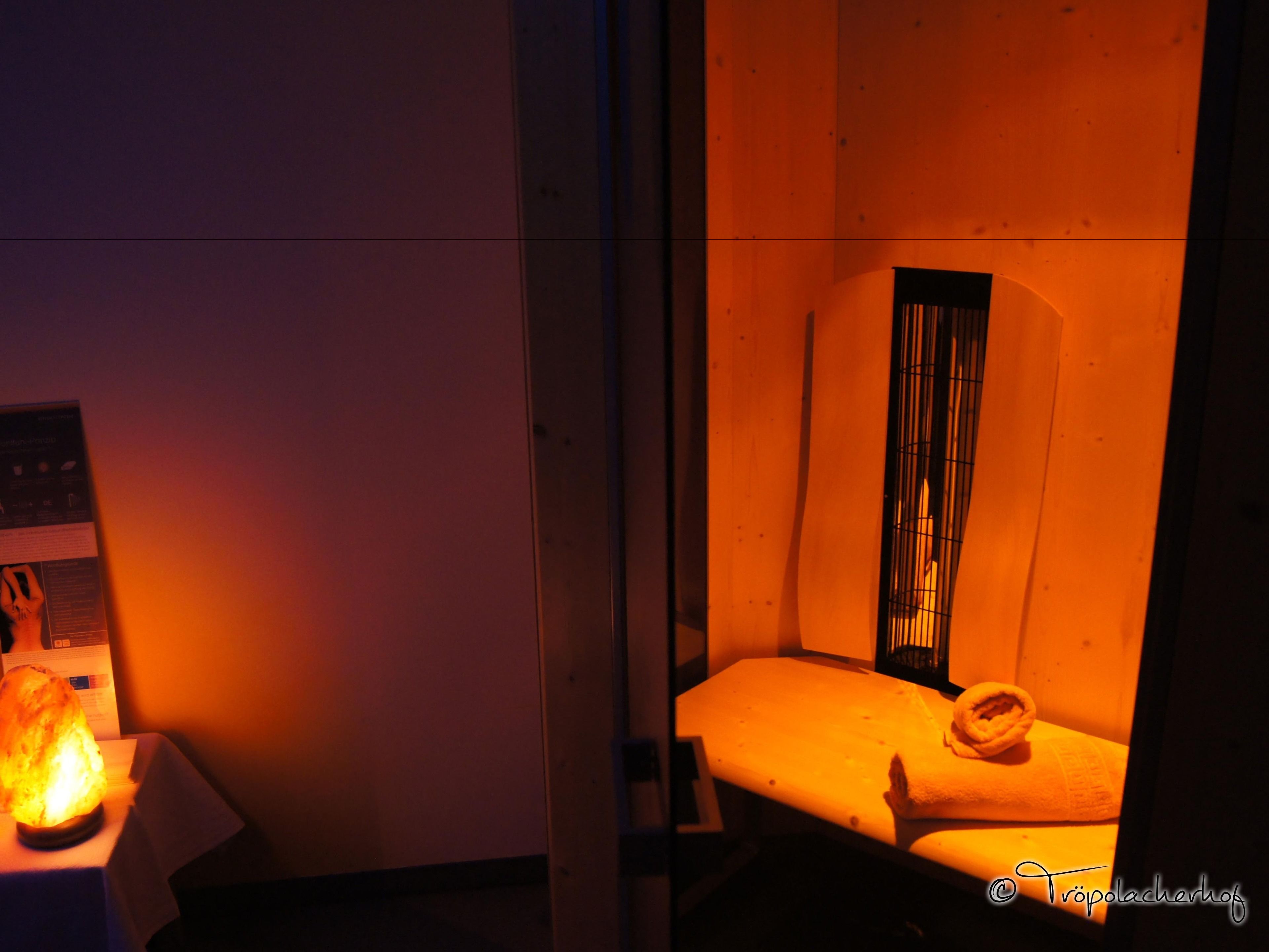 Um quarto com pouca luz, uma cama, um aquecedor e um cartaz na parede.