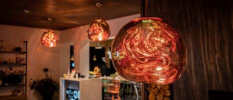 Interior de restaurante com luminárias pendentes esféricas e teto de madeira.
