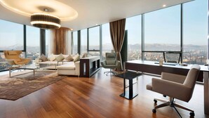 Uma sala de estar ampla com uma grande janela, um lustre moderno e vista para a cidade.