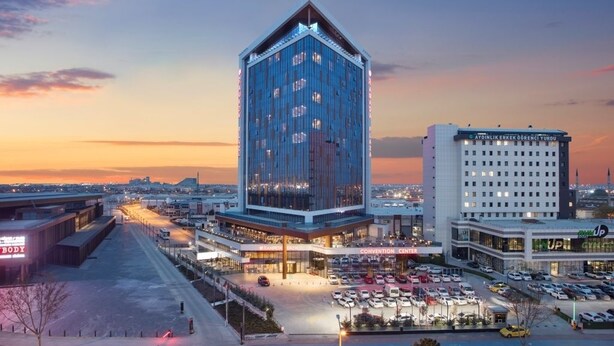 Um hotel moderno com fachada de vidro marcante, centro de convenções e estacionamento.
