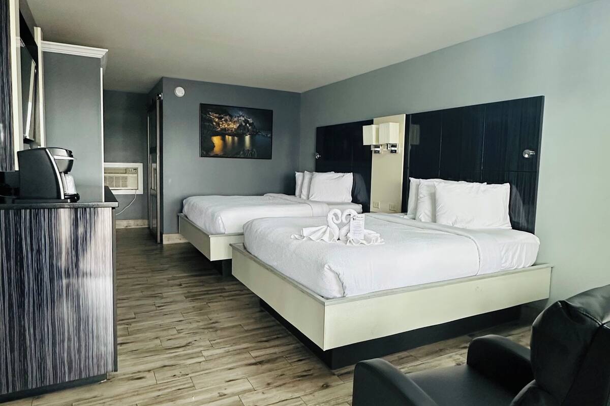 Quarto de hotel com duas camas, uma escrivaninha e um espaço de estar.