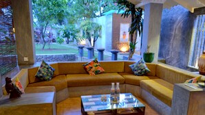 Uma sala de estar moderna com um sofá seccional, uma mesa de centro de vidro e vista para um jardim.