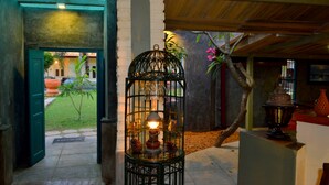 Um candeeiro com luz no interior, colocado sobre um chão de azulejos.