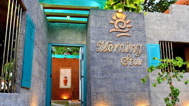 Entrada de pedra com uma placa indicando "Morning Star" e uma porta azul.