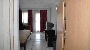 Quarto com cama, televisão, escrivaninha e guarda-roupa.