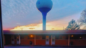 Um edifício com uma grande torre d'água, estacionamento e uma fileira de portas.