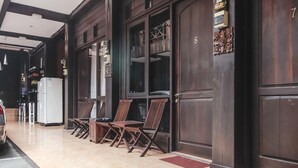Um restaurante com mesas ao ar livre, um carro estacionado nas proximidades e uma porta com placa de número.
