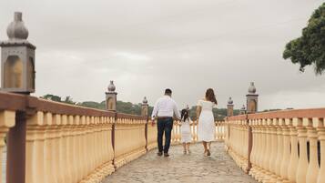 Uma ponte de pedra com grades ornamentadas e uma família caminhando sobre ela.