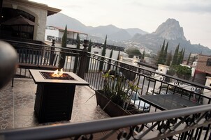 Um terraço no telhado com lareira, plantas em vasos e vista para montanhas.