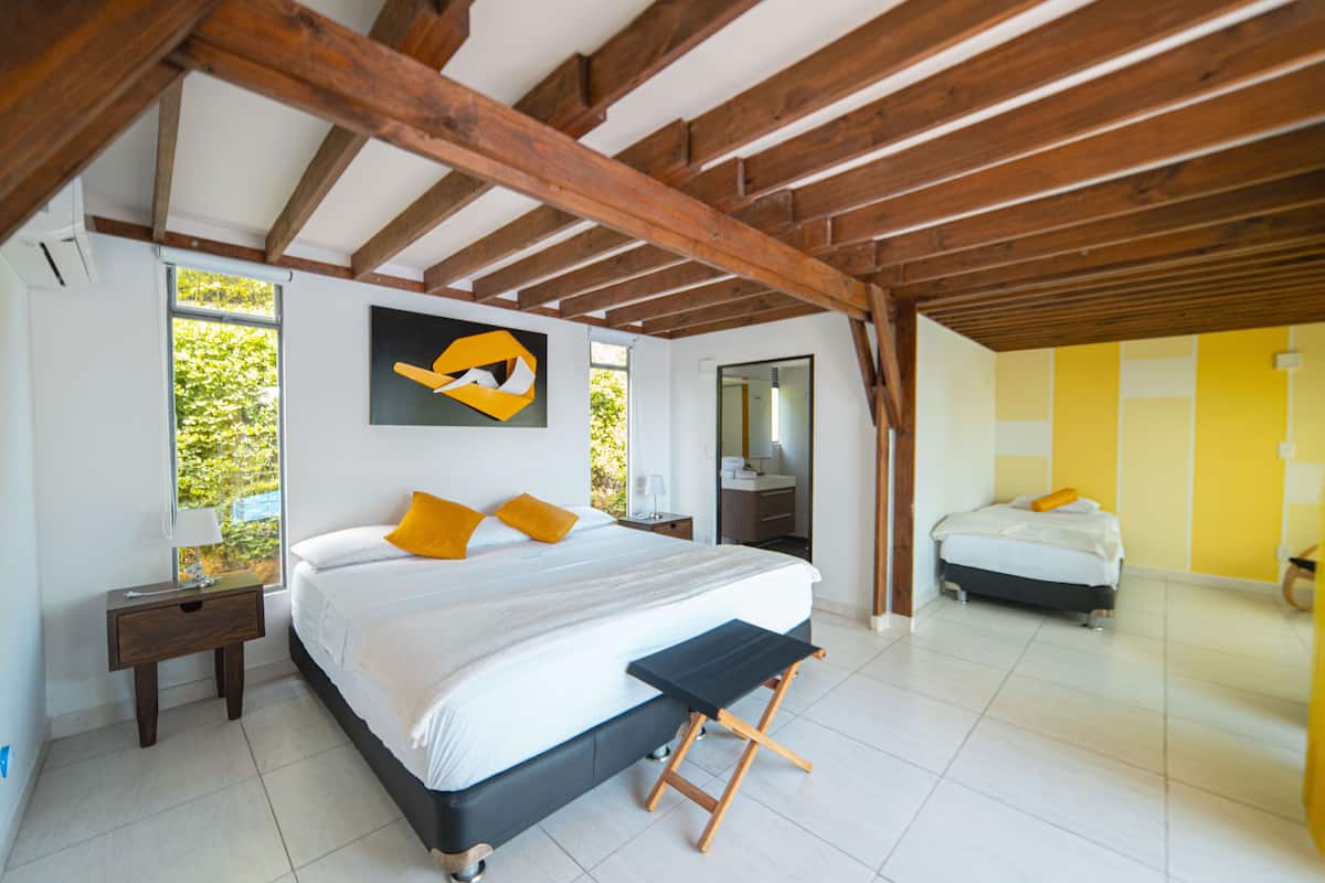 Quarto com cama, vigas de madeira, janela e espelho.