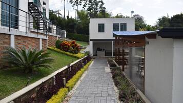 Um edifício moderno com fachada de tijolos, um caminho de pedra e um jardim bem cuidado com diversas plantas e flores.