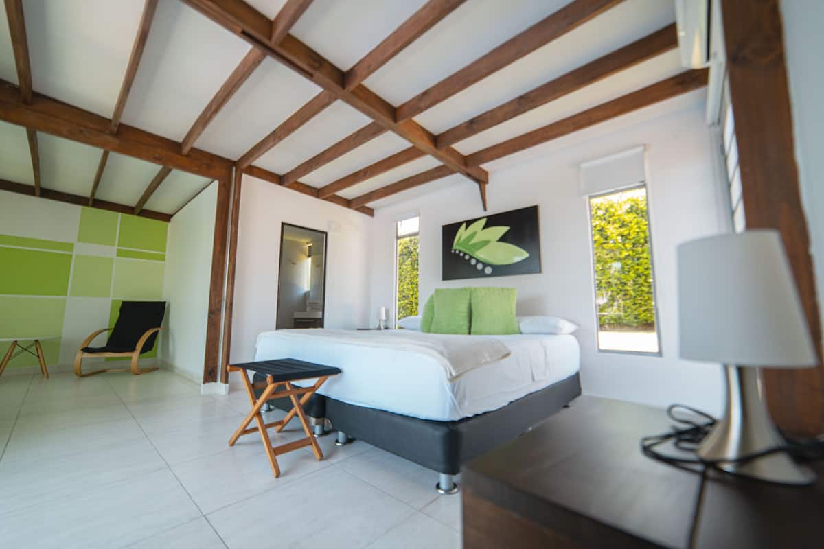 Quarto com cama, cadeira, escrivaninha e janela.