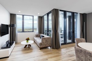 Uma sala de estar moderna com um sofá, uma TV, uma mesa de jantar e vista da cidade através de grandes janelas.