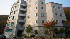 Um hotel com vários andares e design moderno, com varandas no lado esquerdo e fachada de pedra.