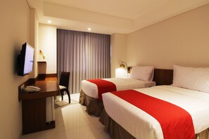 Quarto de hotel com duas camas, uma mesa com telefone, televisão e uma cadeira.