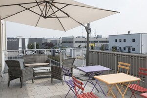Terraço no telhado com móveis de vime, uma mesa e cadeiras.