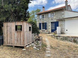Um edifício rústico de pedra com um galpão de madeira em um ambiente rural.
