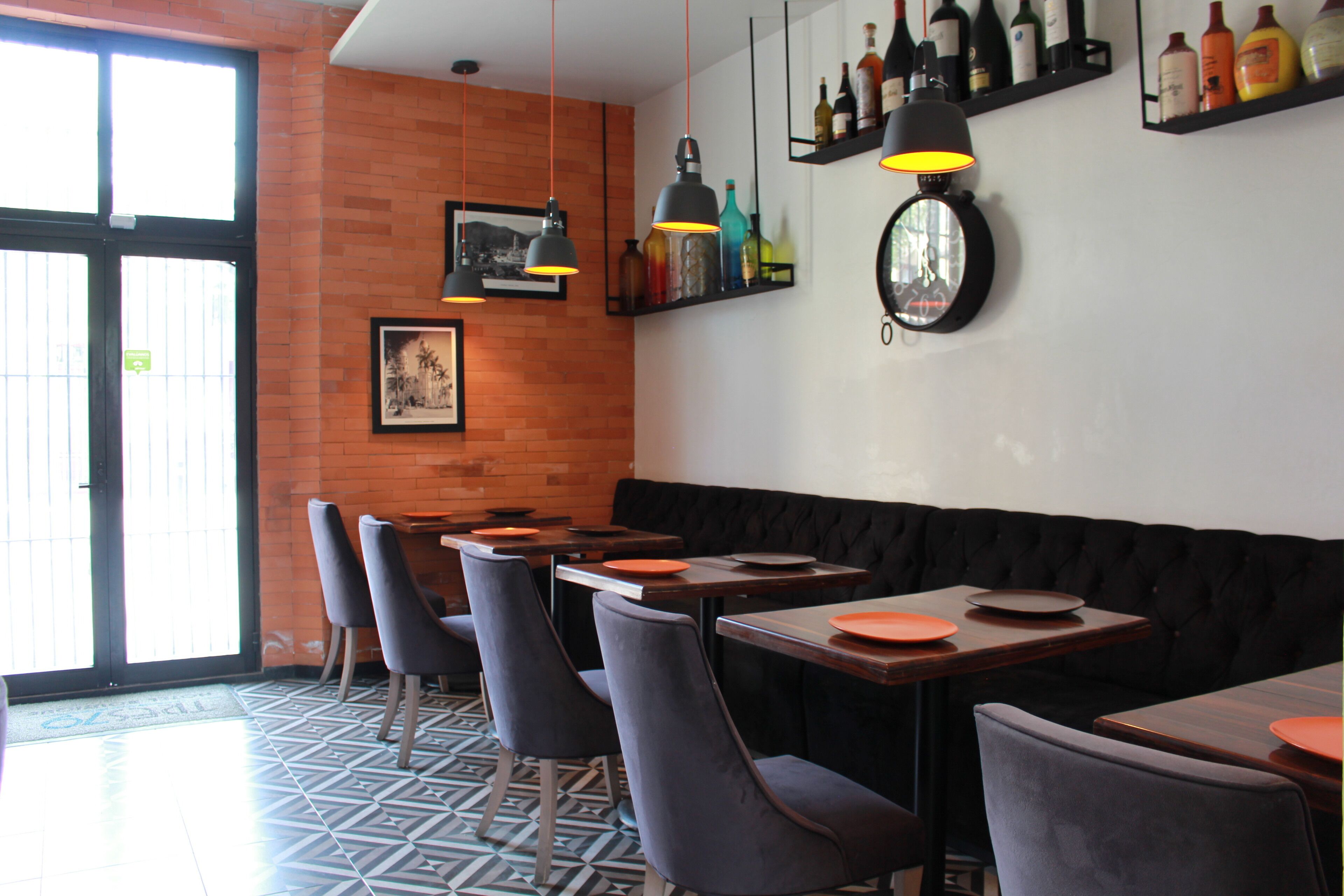 Um restaurante com parede de tijolos, luminárias pendentes e um relógio na parede.