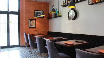 Um restaurante com parede de tijolos, luminárias pendentes e um relógio na parede.