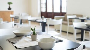 Uma sala de jantar moderna com móveis brancos, uma planta de cacto e uma tigela sobre a mesa.