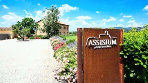 Placa de Assisi Agriturismo com vista para um edifício e jardim paisagístico.