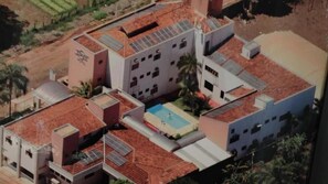 Um edifício de vários andares com telhado plano, painéis solares e uma pequena área de piscina.
