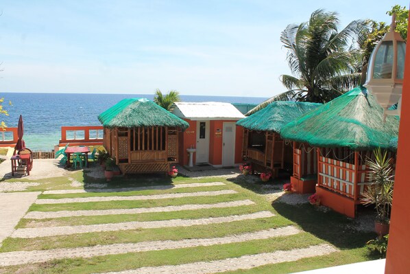 Uma propriedade à beira-mar com cabanas de telhado de palha, um caminho pavimentado e vista para o oceano.