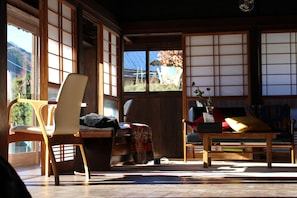 Um quarto japonês tradicional com tatames, uma mesa de madeira baixa e um sofá com almofadas.